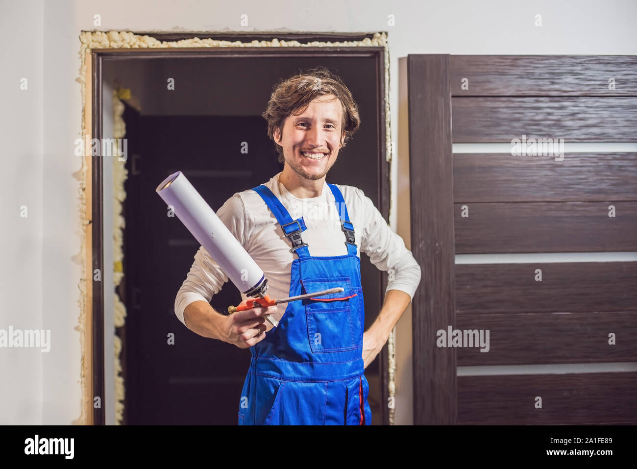 Young handyman installing door with an mounting foam in a room Stock ...
