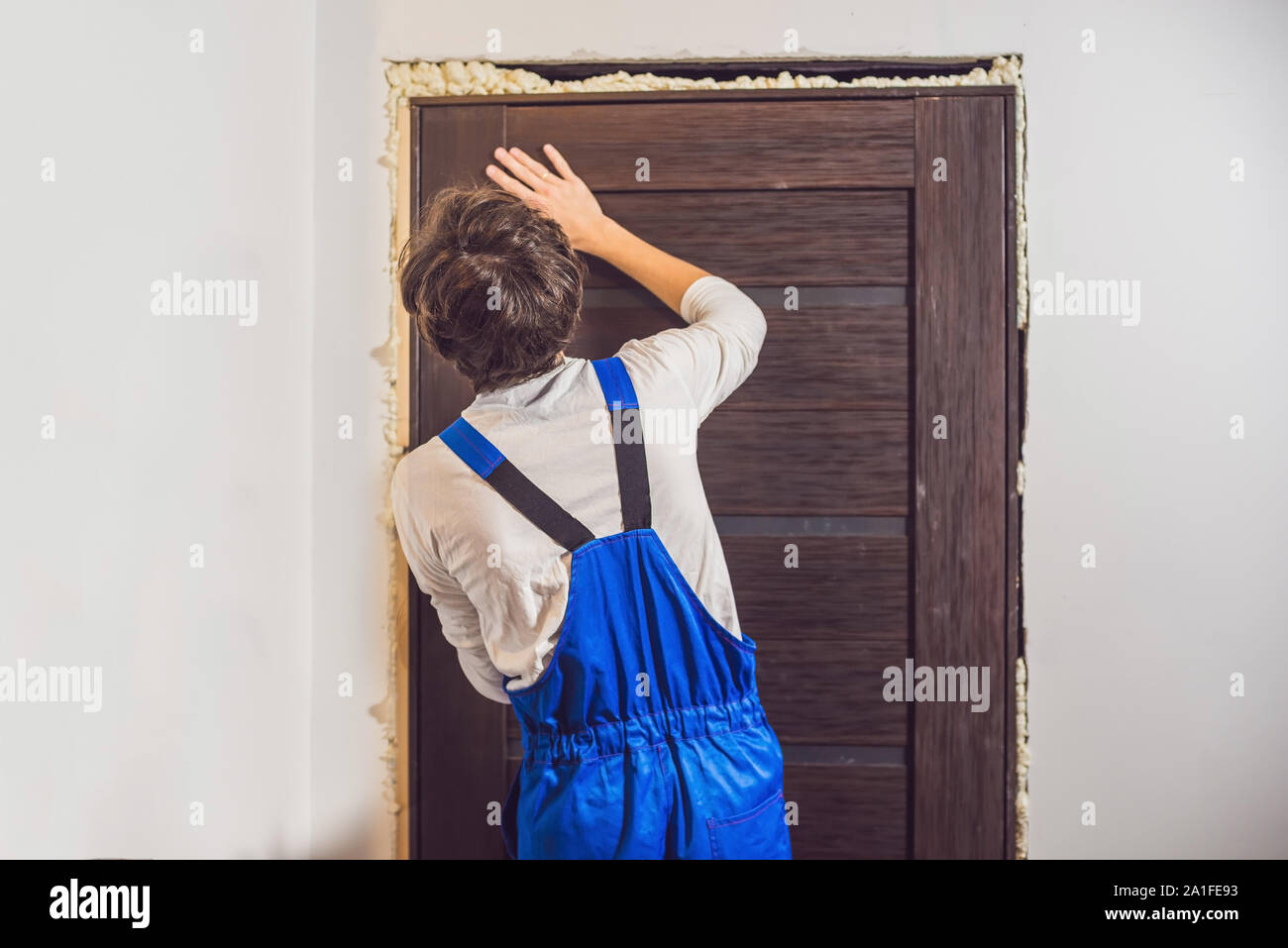 Young handyman installing door with an mounting foam in a room Stock ...