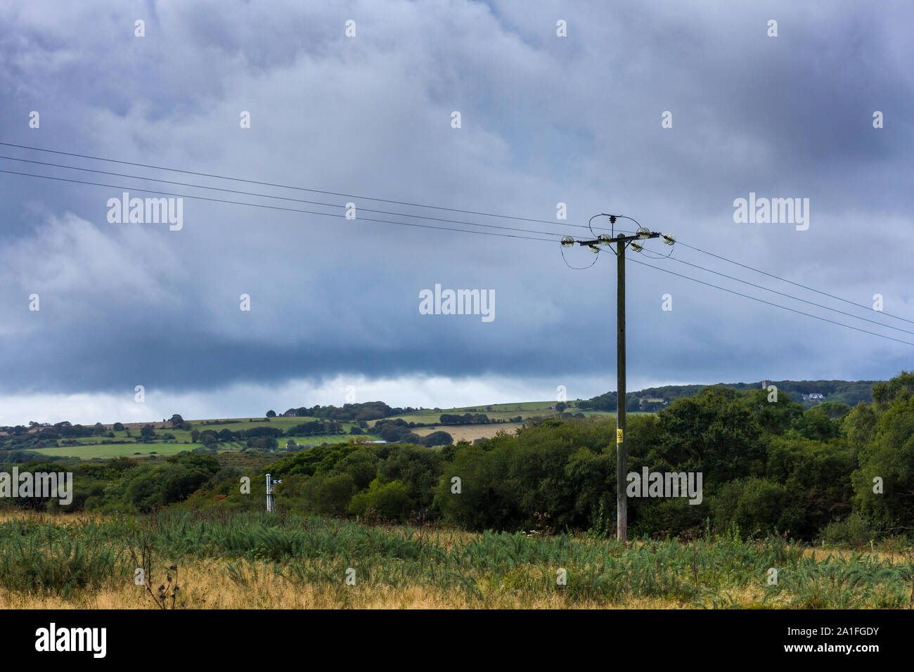 Power lines crossing countryside with rain, storm clouds, Dorset ...