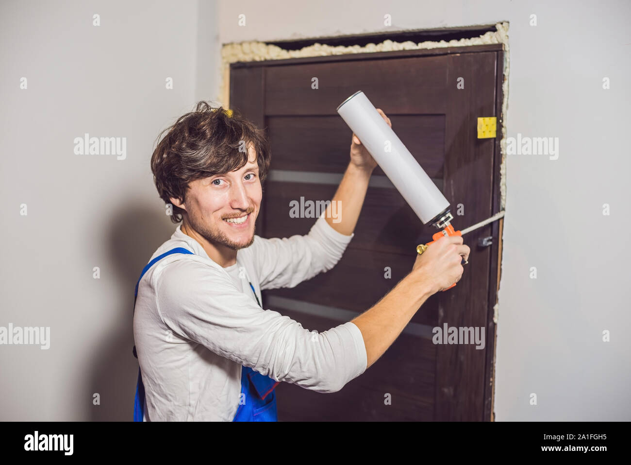 Young handyman installing door with an mounting foam in a room Stock ...