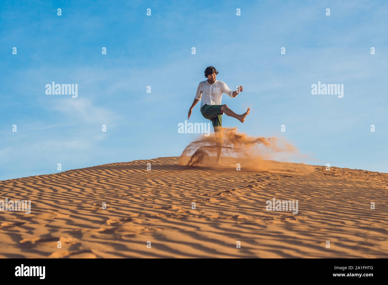 A man is kicking sand in a red desert. Splash of anger concept Stock ...