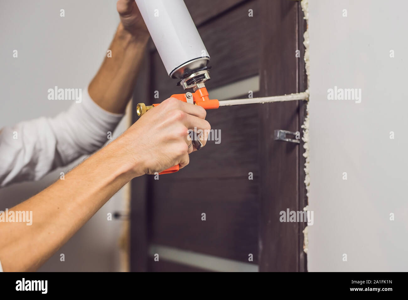 Young handyman installing door with an mounting foam in a room Stock ...