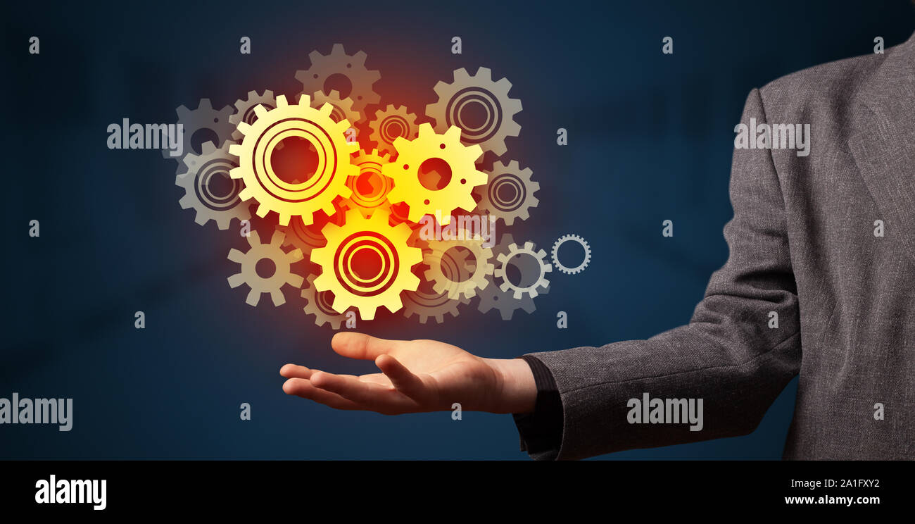 Hand holding gears in his hand Stock Photo - Alamy