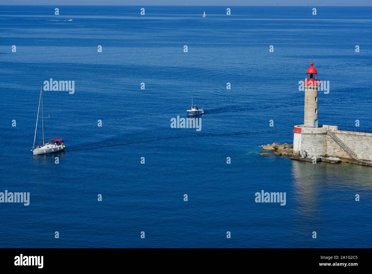 Two boats passing a lighthouse Stock Photo - Alamy