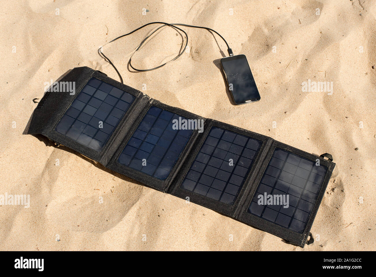 Portable solar panel is on the beach in the sand and charges the ...