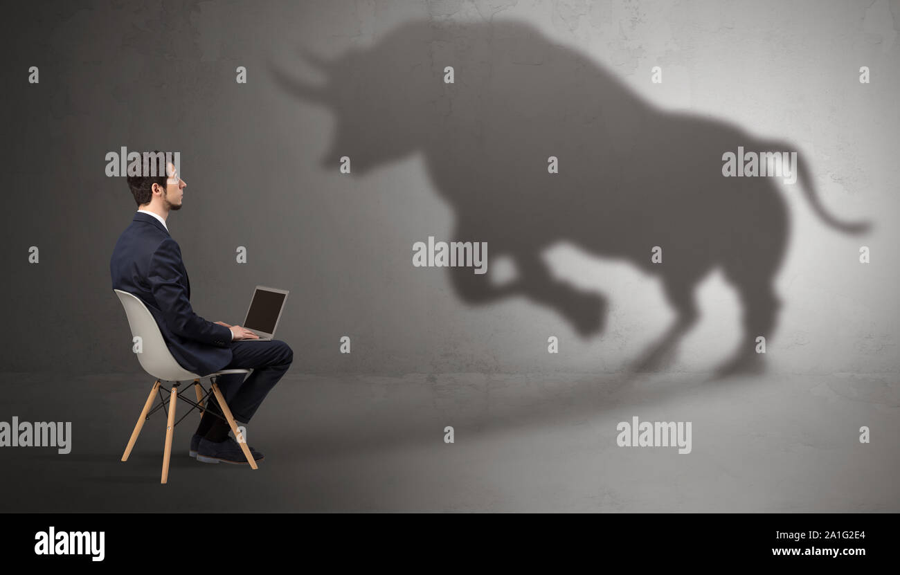 Humble businessman staying and offering stuffs to a huge angry bull ...