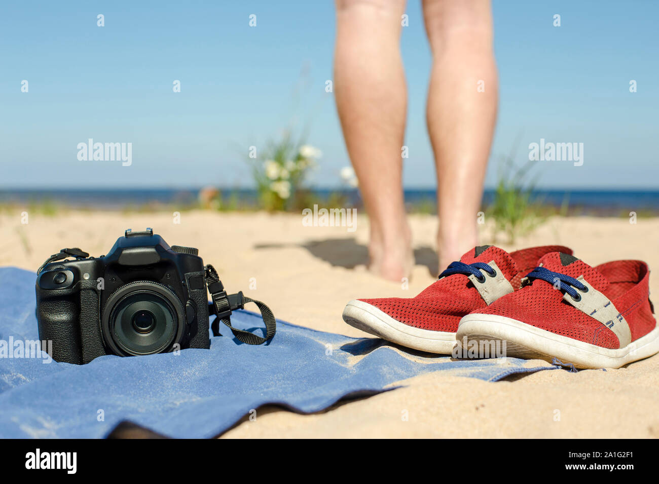 Camera with lens lying a towel on the sand at the beach, standing ...