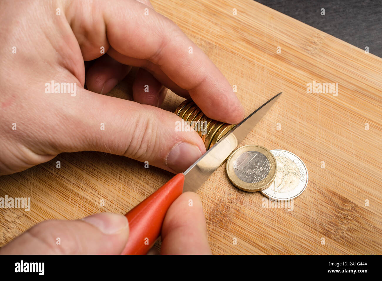hand cut euro coins with a knife on a cutting board, separating them as ...