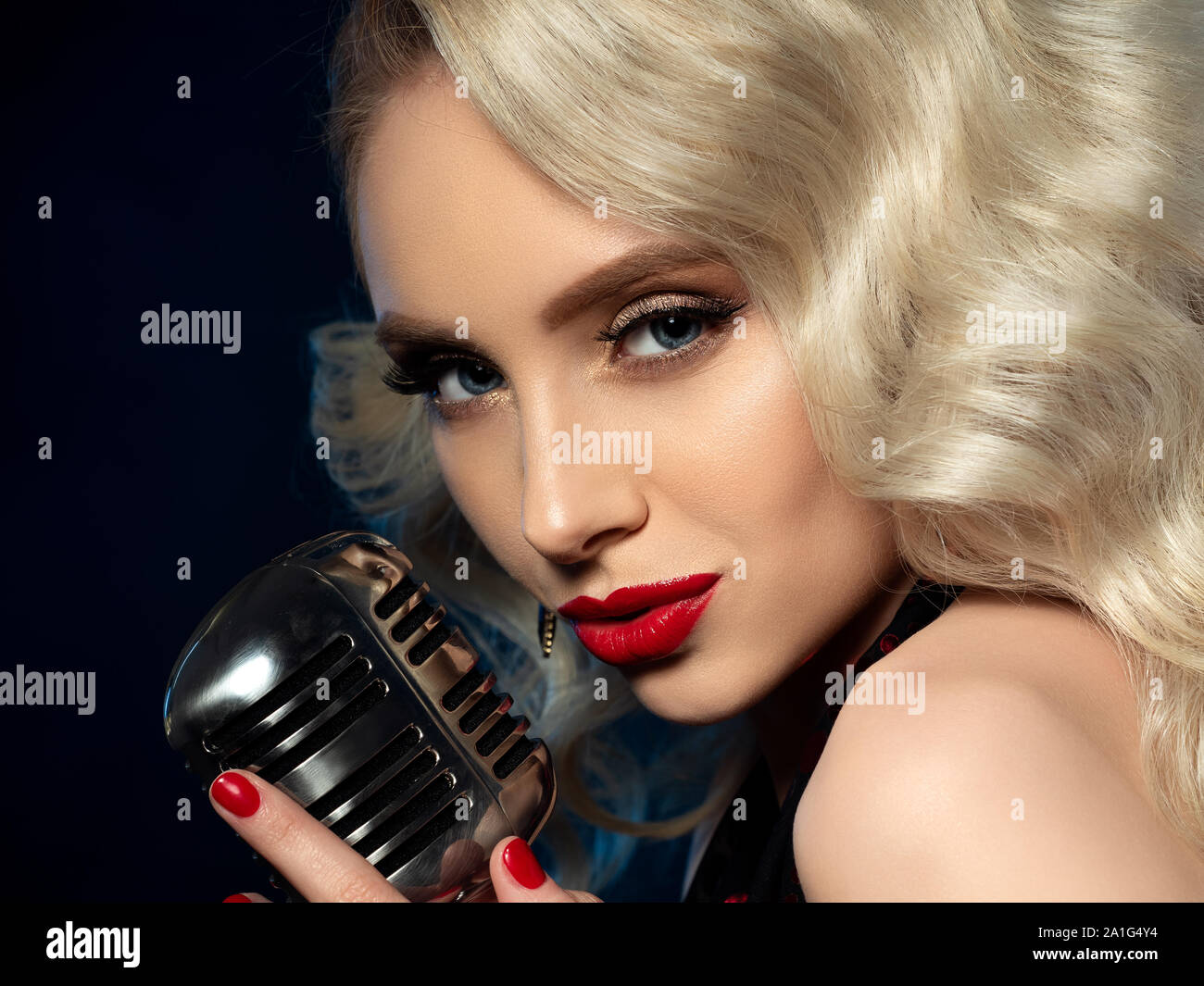 Portrait of pretty blond female singer holding microphone Stock Photo ...