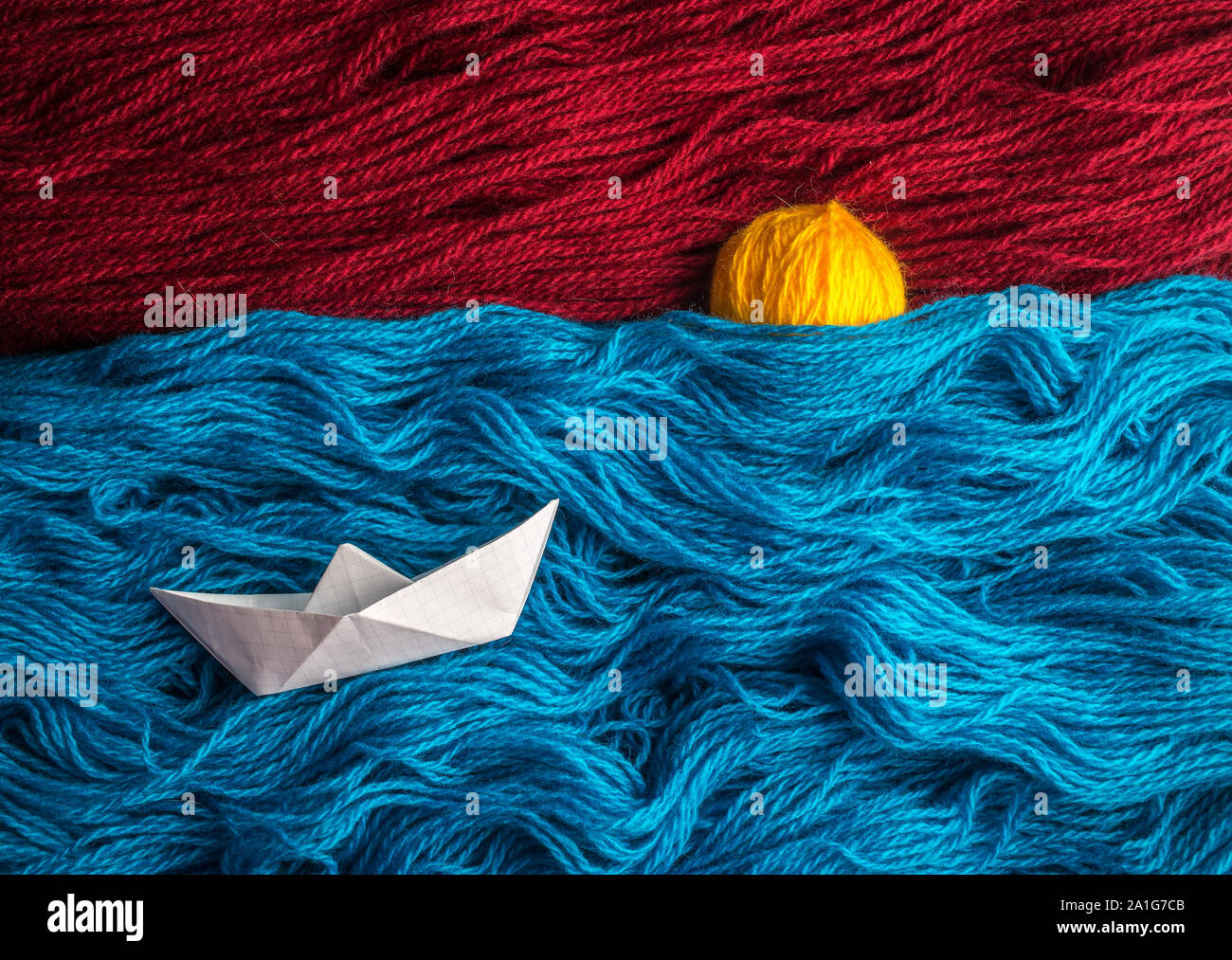 Cute white of origami boat floating on the waves of woolen yarn, on the ...