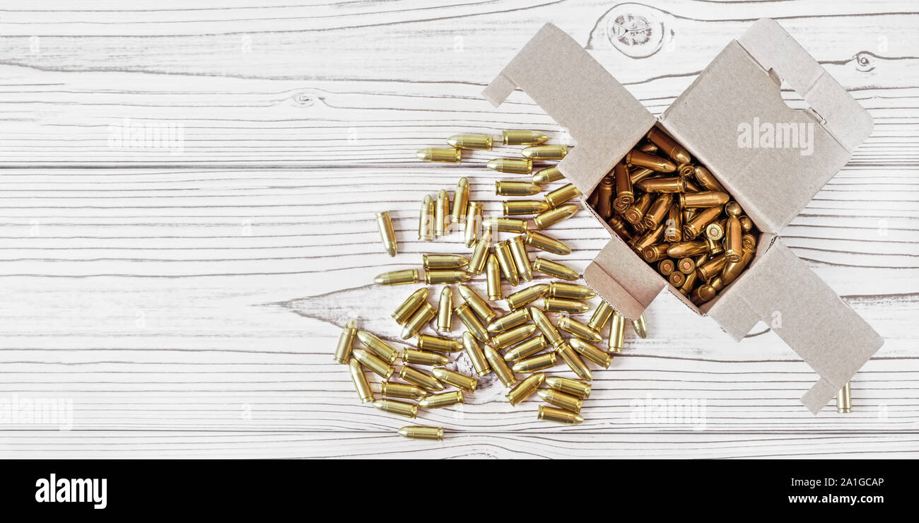Top down view, carton box with yellow brass ammunition bullets on white ...