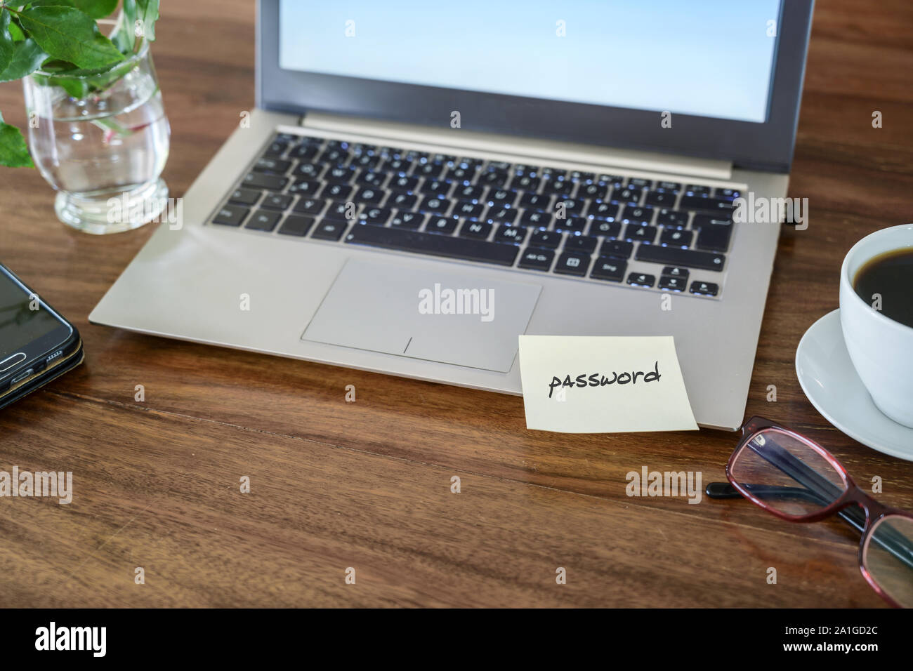 password written on a sticky note and taped to the laptop on a wooden ...