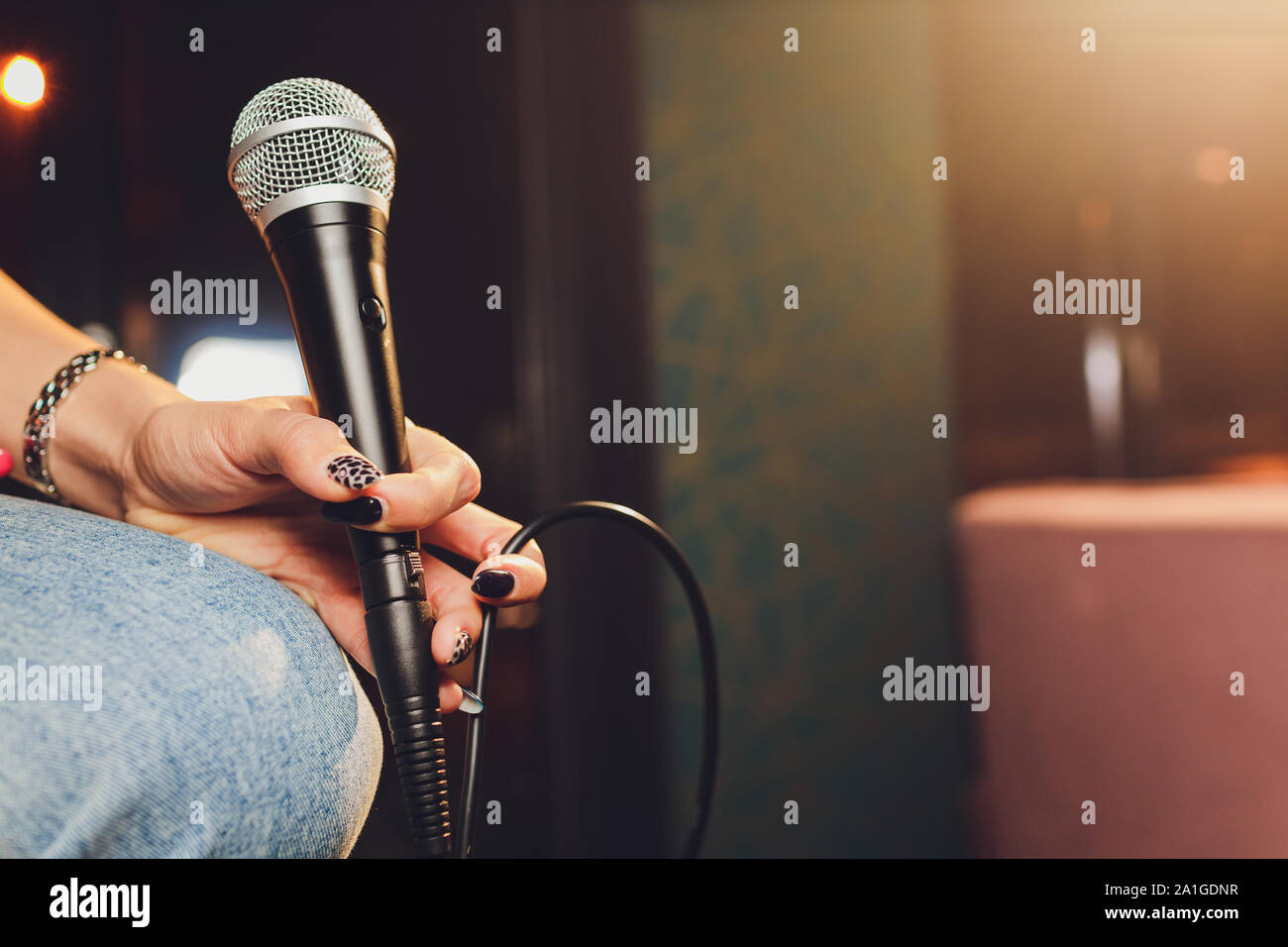Young woman singing in karaoke and holding a microphone close-up ...