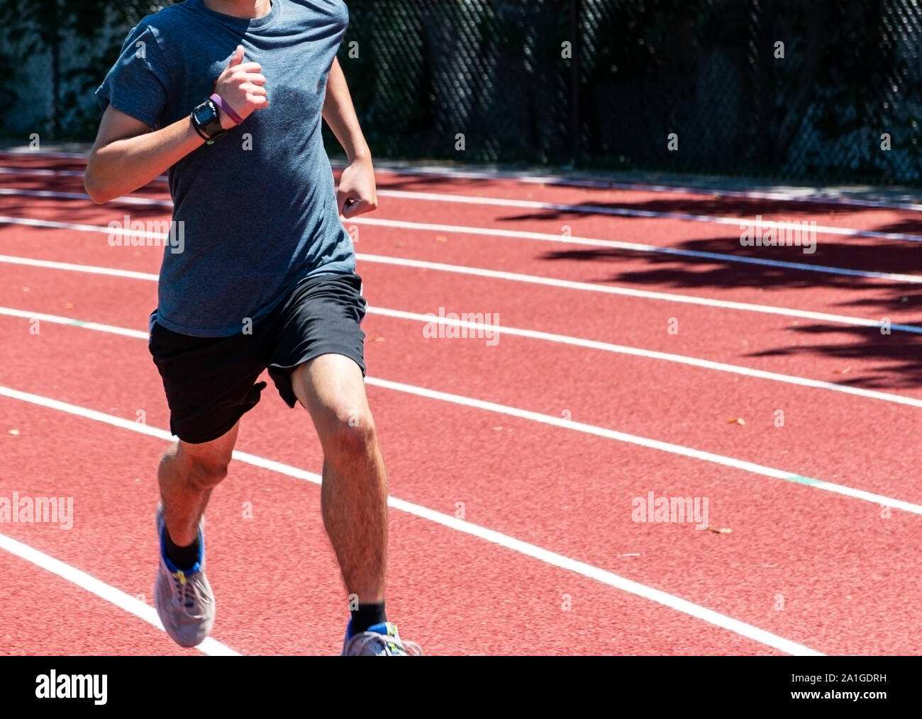 A high school track runner is running clockwise on a red track Stock ...