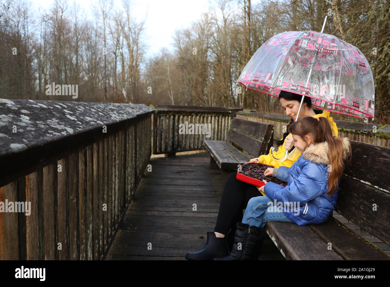 Two sisters enjoying some chocolate on a cool day in a park Stock Photo ...