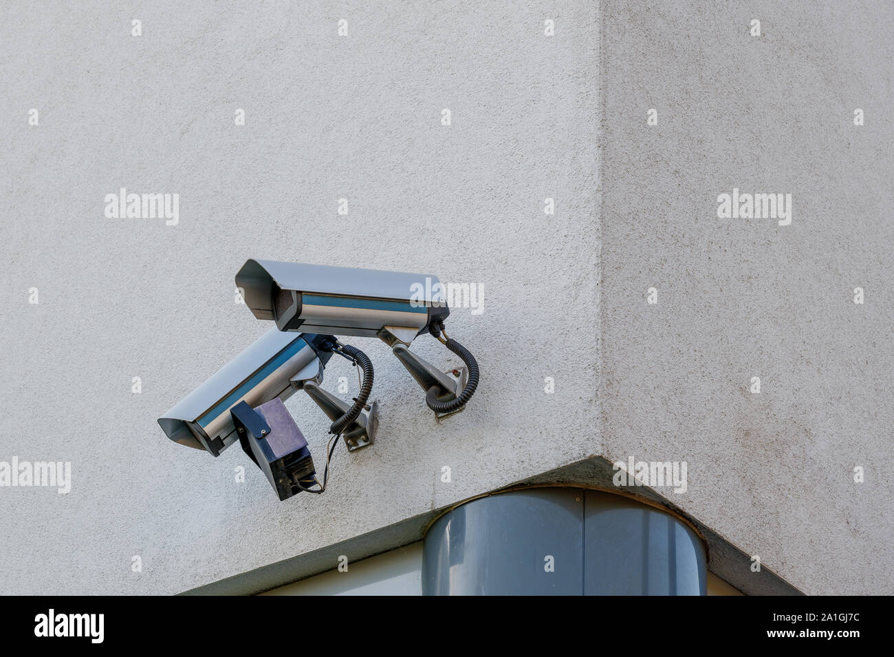 Two Security Cameras set up on the exterior dirty white rough concrete ...
