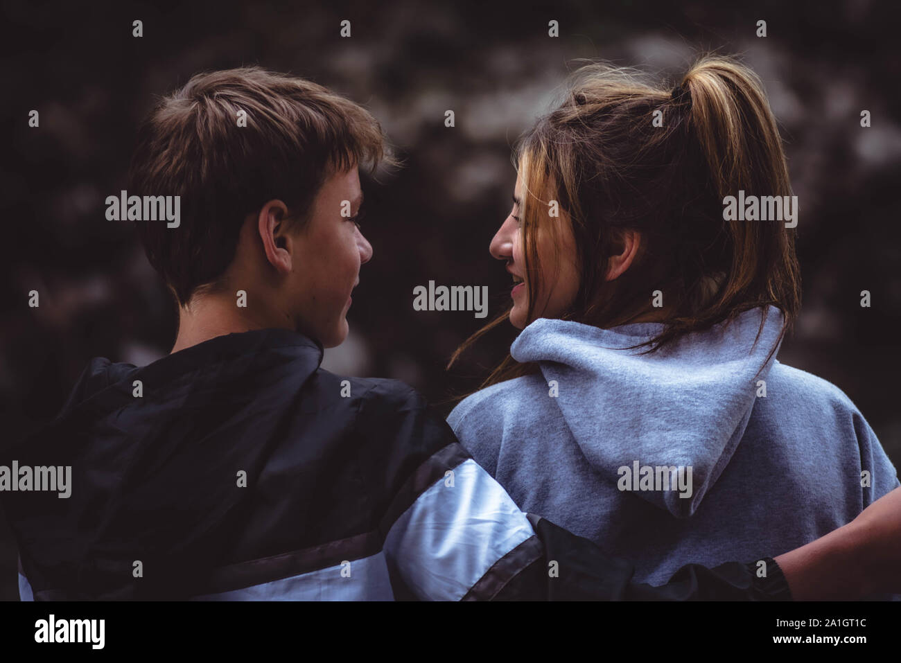 The close up of the backs of the teenage girl and boy hugging outside ...