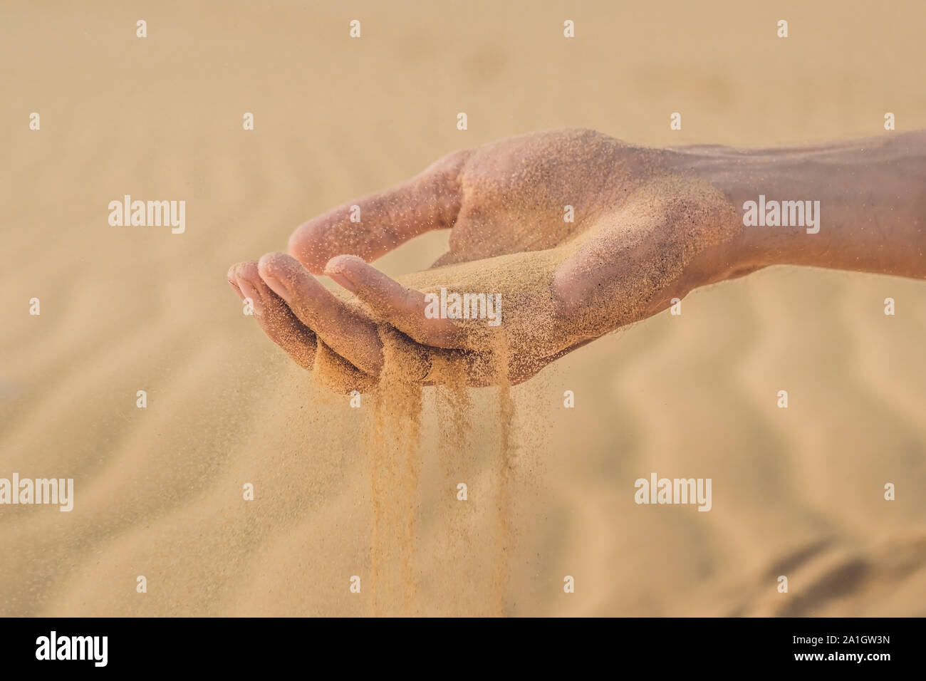 Desert, sand puffs through the fingers of a man's hand Stock Photo - Alamy
