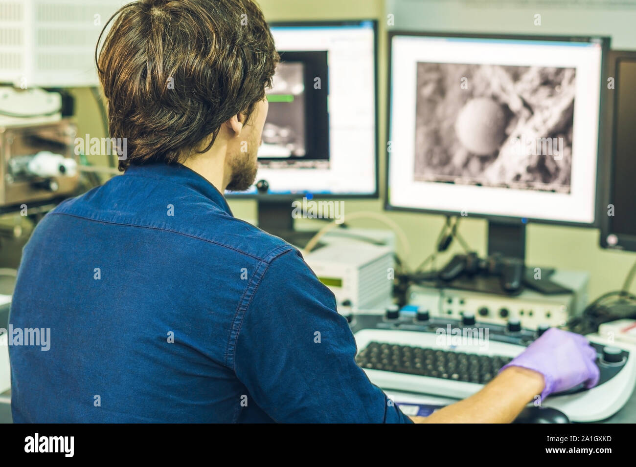 Scientist works at a electron microscope control pannel with two ...