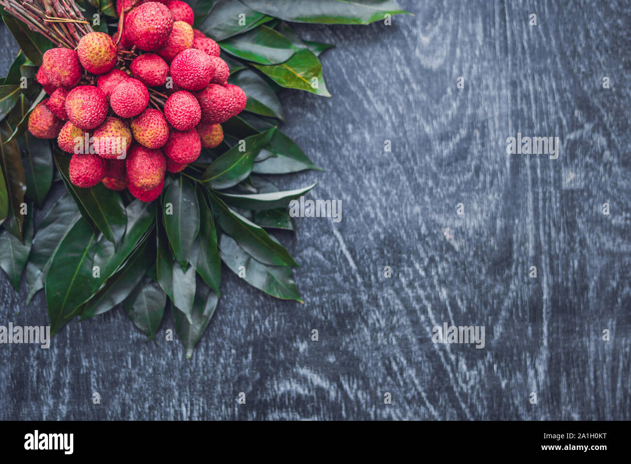 Fresh organic lychee fruit and lychee leaves on a rustic wooden ...