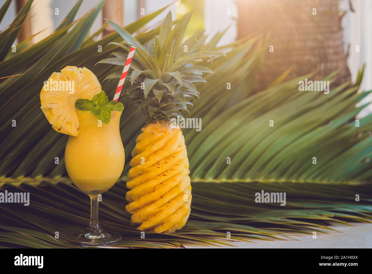 Pineapple and pineapple smoothies against the background of a branch of ...