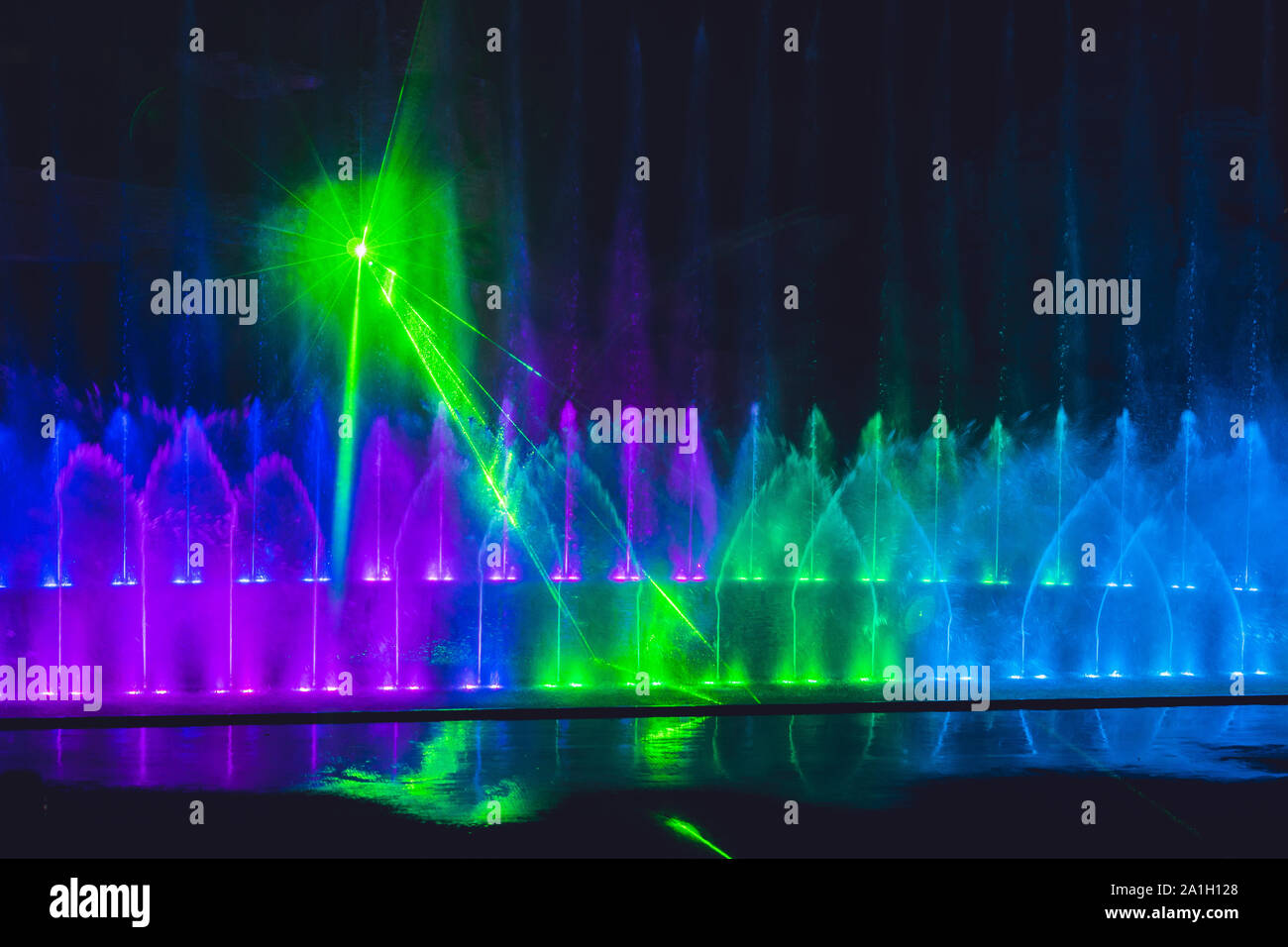 Multicolored dancing water jet fountain in the dark Stock Photo - Alamy