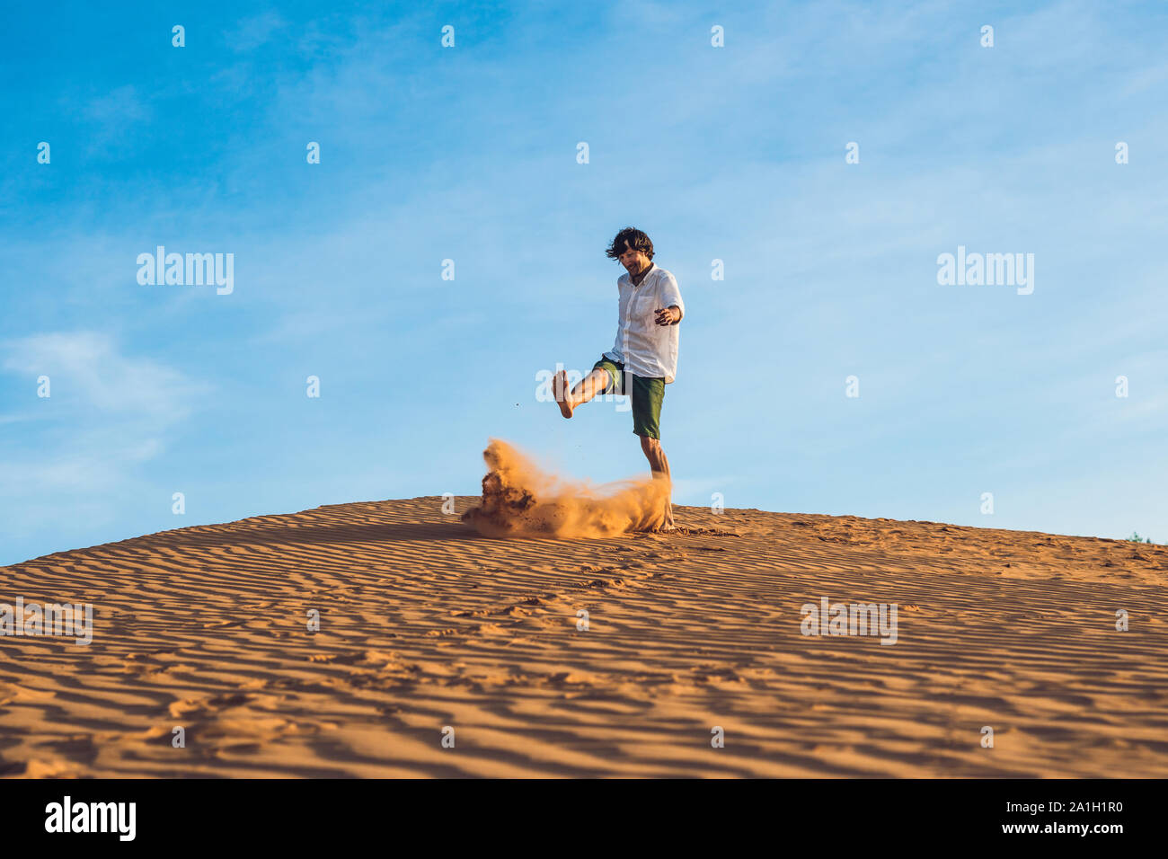 A man is kicking sand in a red desert. Splash of anger concept Stock ...