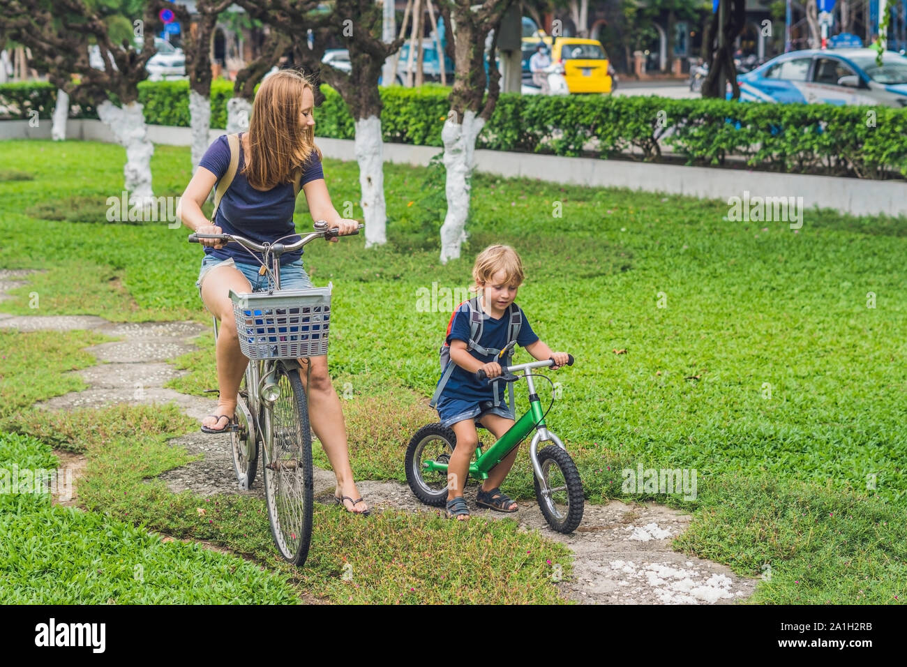 Happy family is riding bikes outdoors and smiling. Mom on a bike and ...