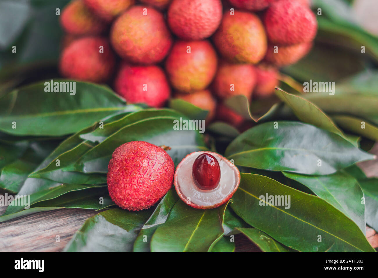 Fresh organic lychee fruit and lychee leaves on a rustic wooden ...