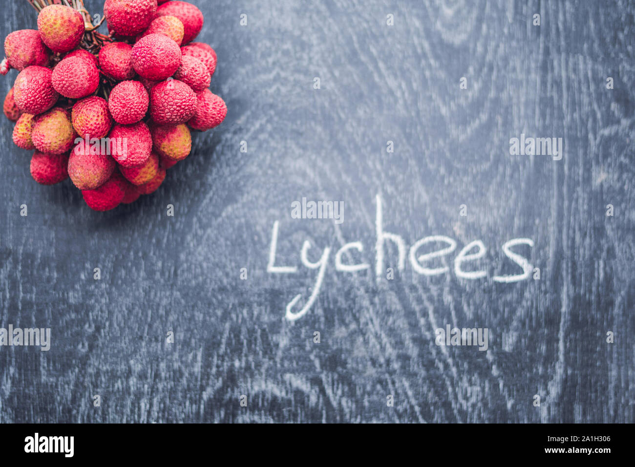 Fresh organic lychee fruit and lychee leaves on a rustic wooden ...