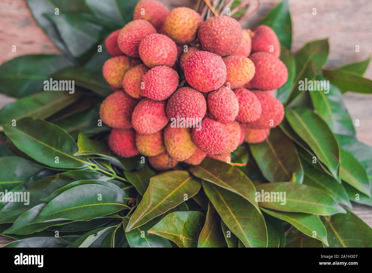 Fresh organic lychee fruit and lychee leaves on a rustic wooden ...