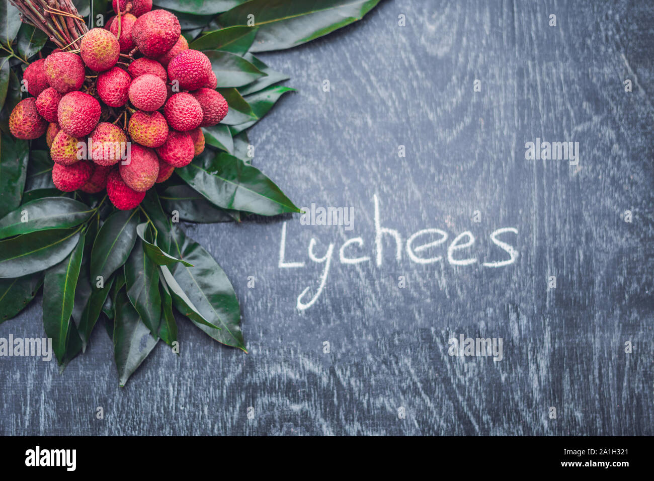 Fresh organic lychee fruit and lychee leaves on a rustic wooden ...