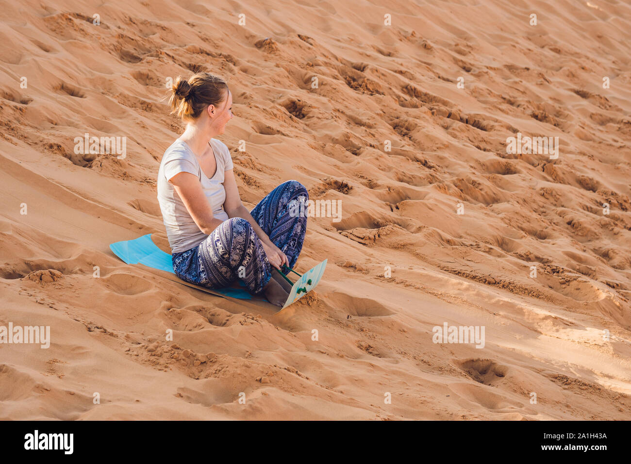 Young woman rolls on a toboggan in the sledge in the desert Stock Photo ...