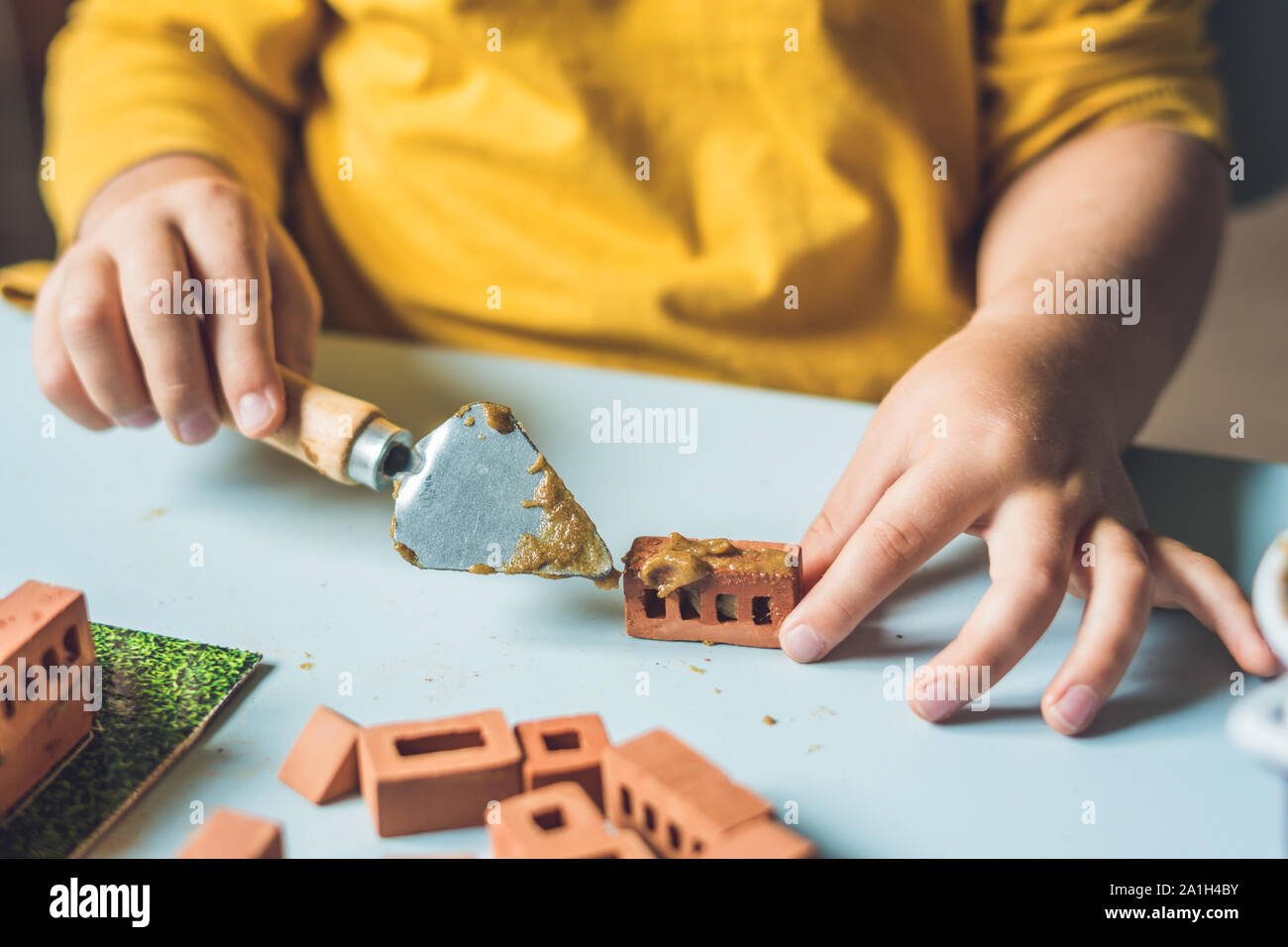 Close up of child's hands playing with real small clay bricks at the ...