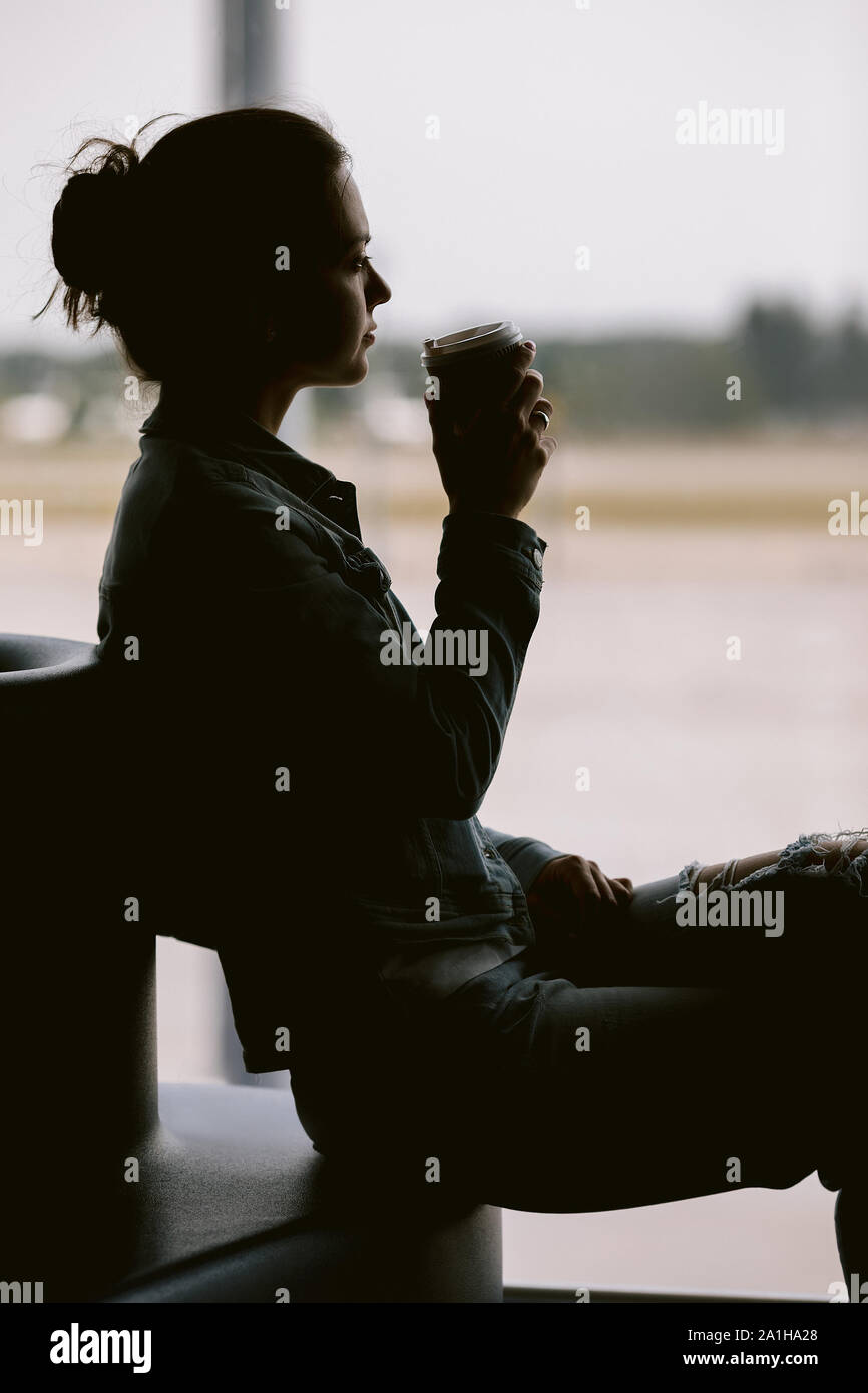 silhouette of woman waiting for flight aircraft. Airline passenger girl ...