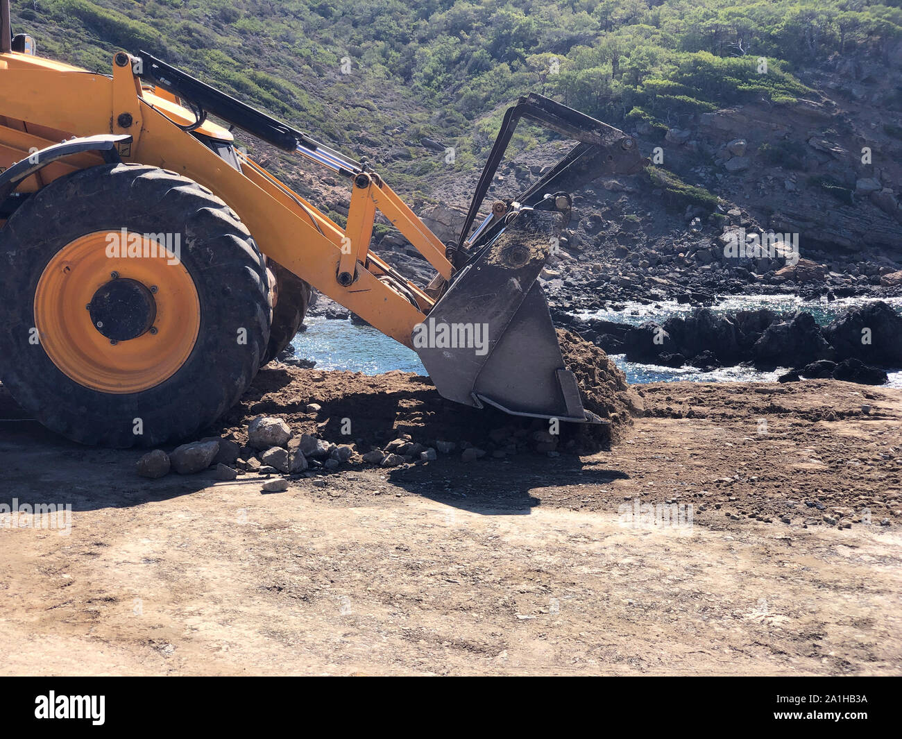 Yellow loader backhoe is planning a road surface during road ...