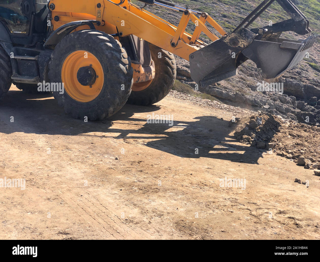 Yellow loader backhoe is planning a road surface during road ...