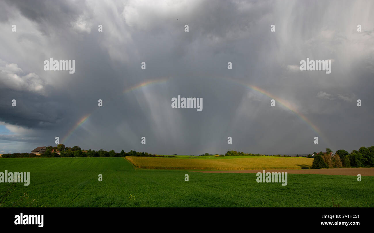 rainbow over a green and yellow field with grey clouds dramatic in fall ...