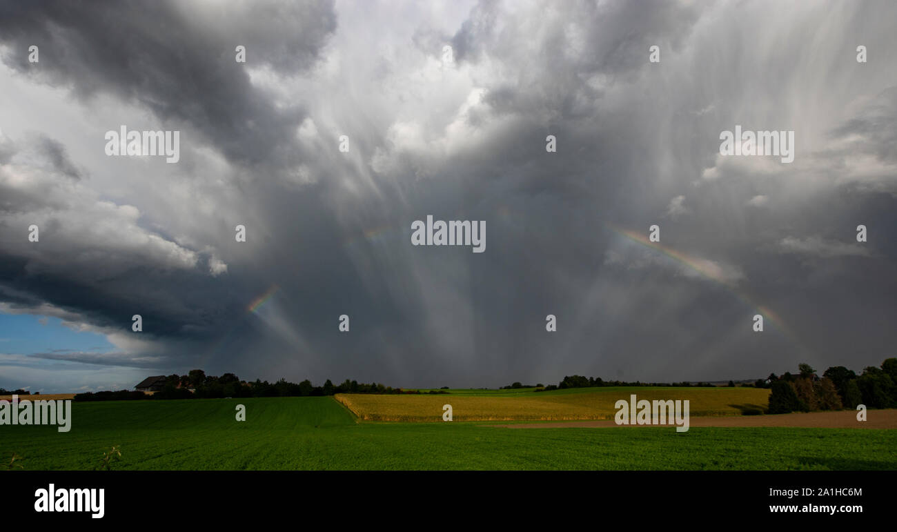 rainbow over a green and yellow field with grey clouds dramatic in fall ...
