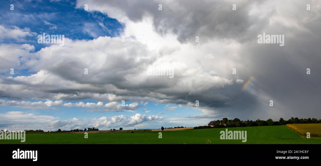 rainbow over a green and yellow field with grey clouds dramatic in fall ...