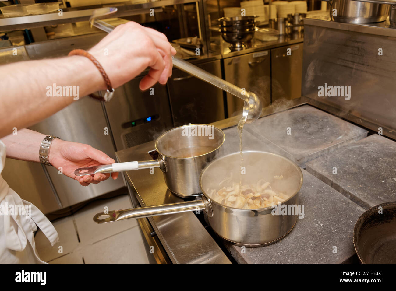 Chef is pouring broth in pot with mushrooms Stock Photo - Alamy