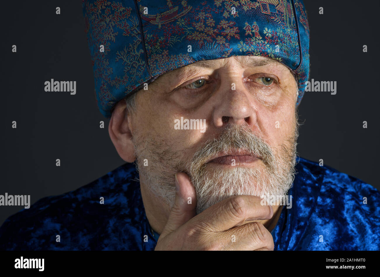 Nice low key portrait of meditating senior man in blue oriental clothes ...