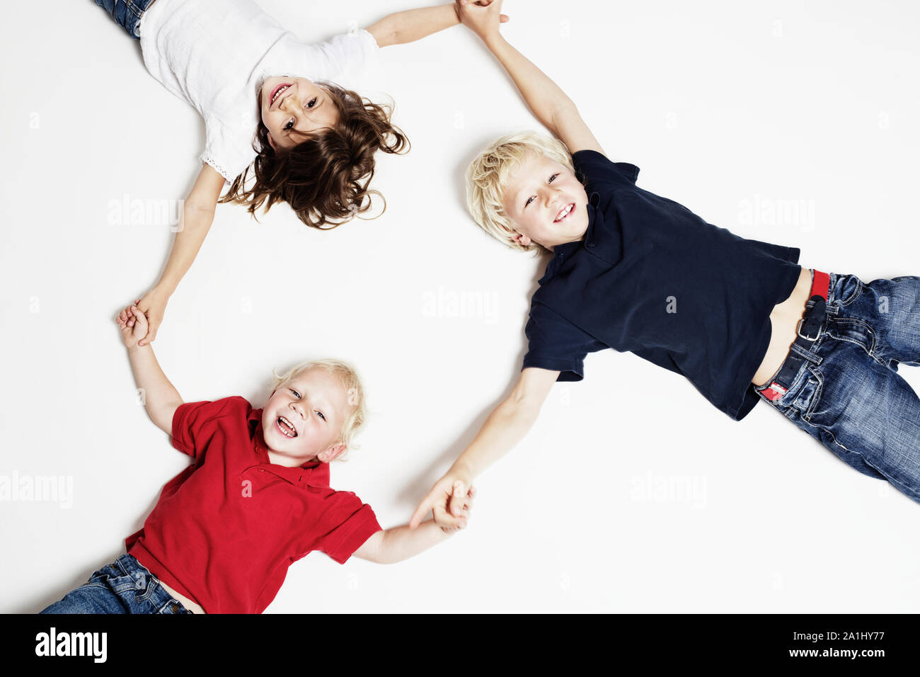 Smiling children on floor holding hands Stock Photo - Alamy