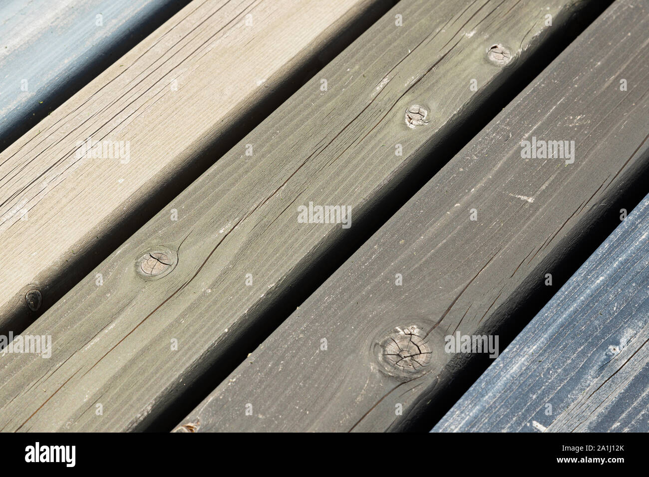 Diagonal view of wooden boards of dull colors olive, beige and blue ...