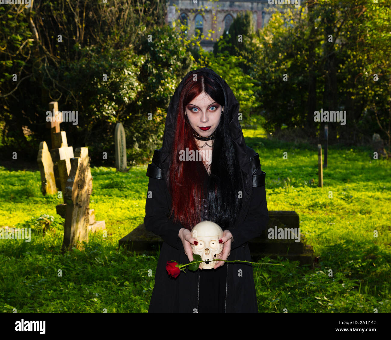 Dark and mysterious young female dressed in black goth costume talks to ...