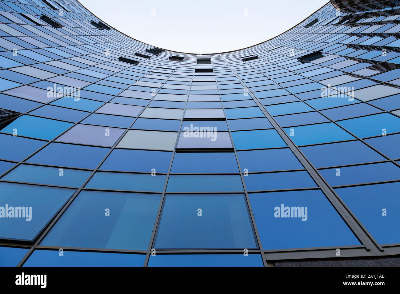 Bottom view of blue glass surface of semicircle building front wall ...