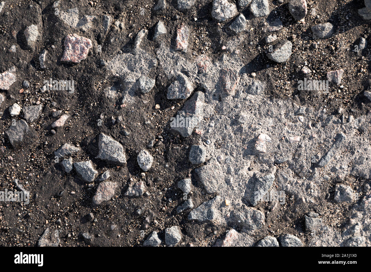 Worn cracked asphalt pavement with dark gravel Stock Photo - Alamy