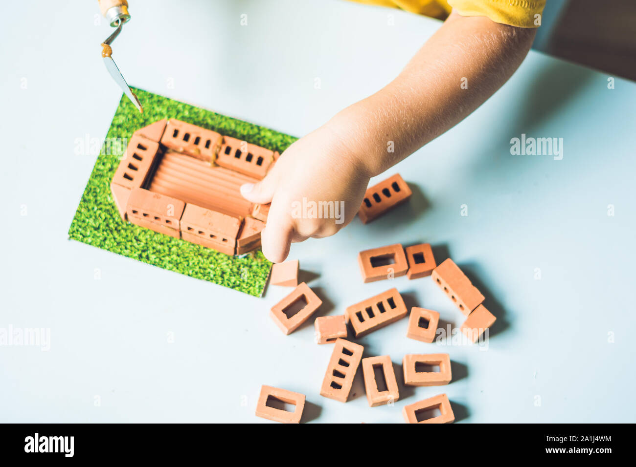 Close up of child's hands playing with real small clay bricks at the ...