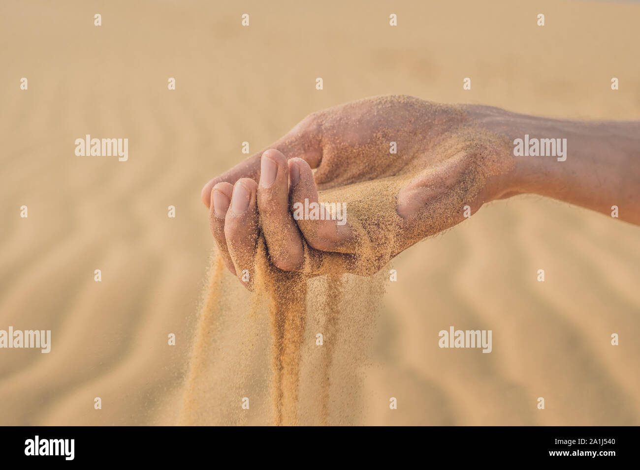Desert, sand puffs through the fingers of a man's hand Stock Photo - Alamy