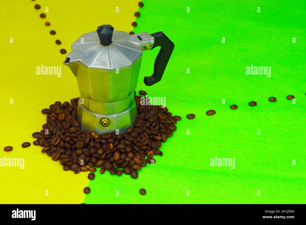 small traditional italian coffee pot on green and yellow background ...